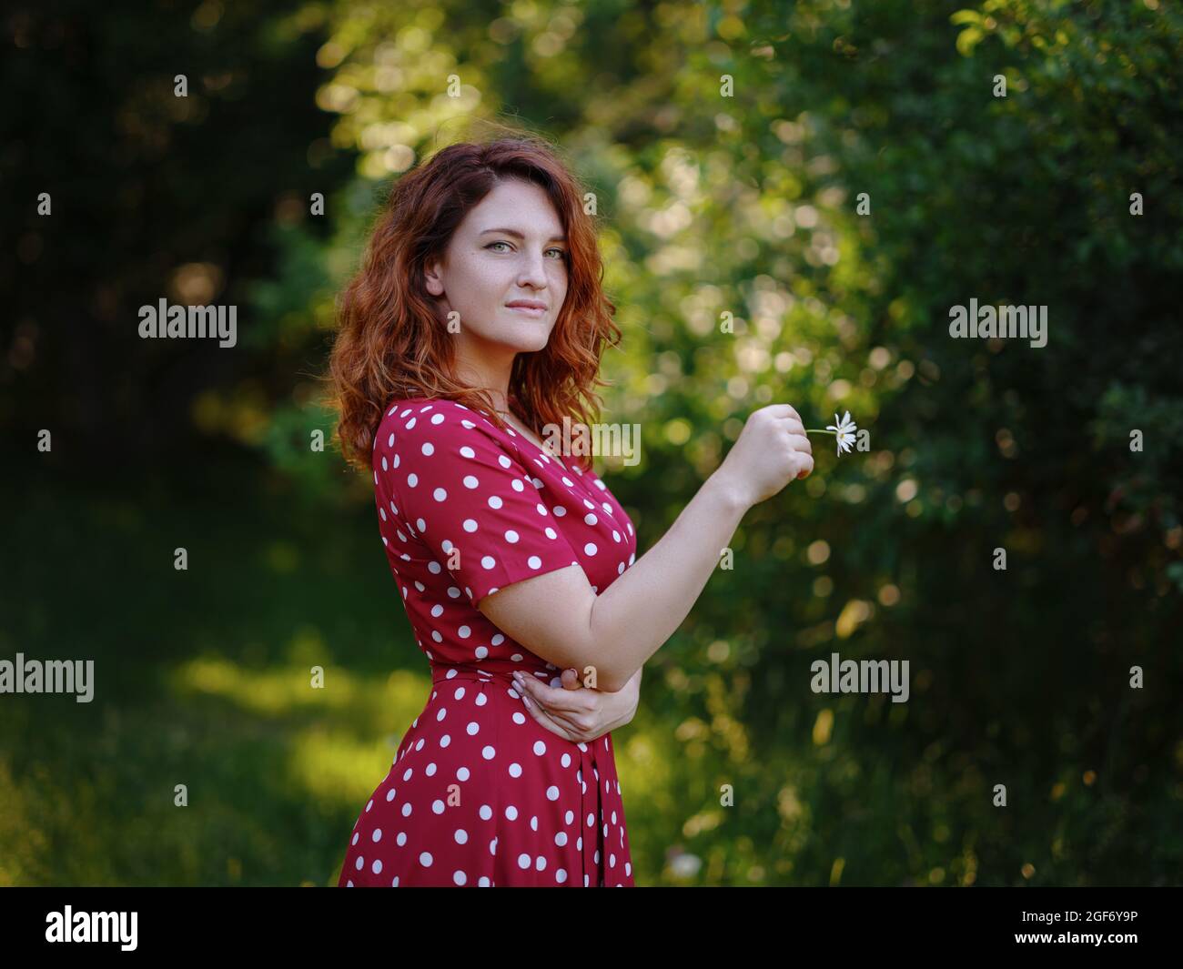Ginger Woman wearing orange dress in green forest enjoys the silence ...
