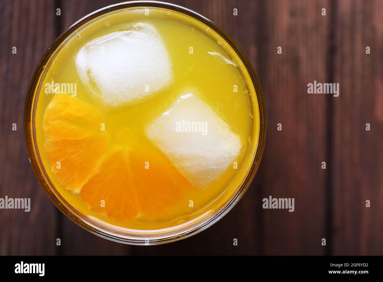 Glass of orange juice with ice blocks and fruit slice on wooden ...