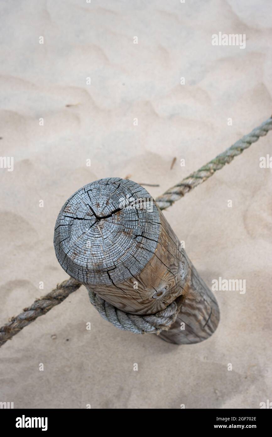 A wooden post with stretched ropes separating the hiking trail from the ...