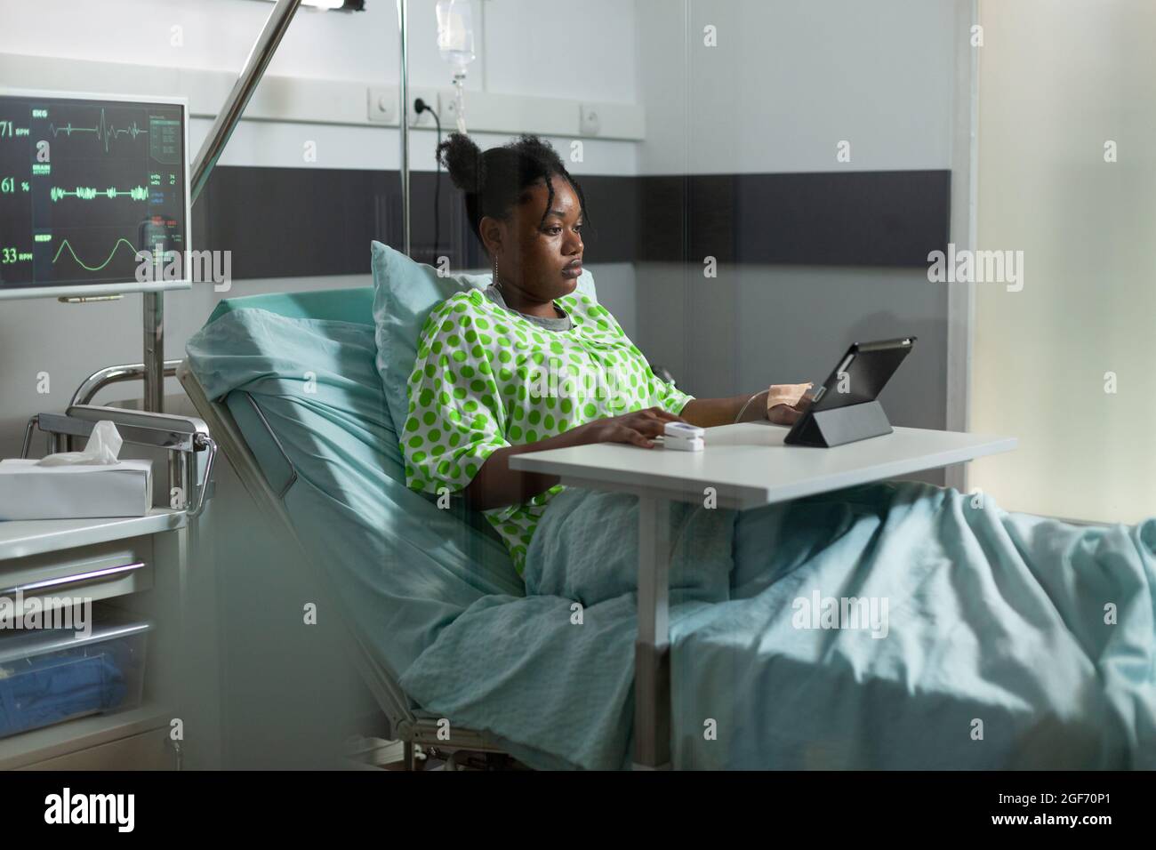 Young african american woman using tablet in hospital ward bed. Sick ...