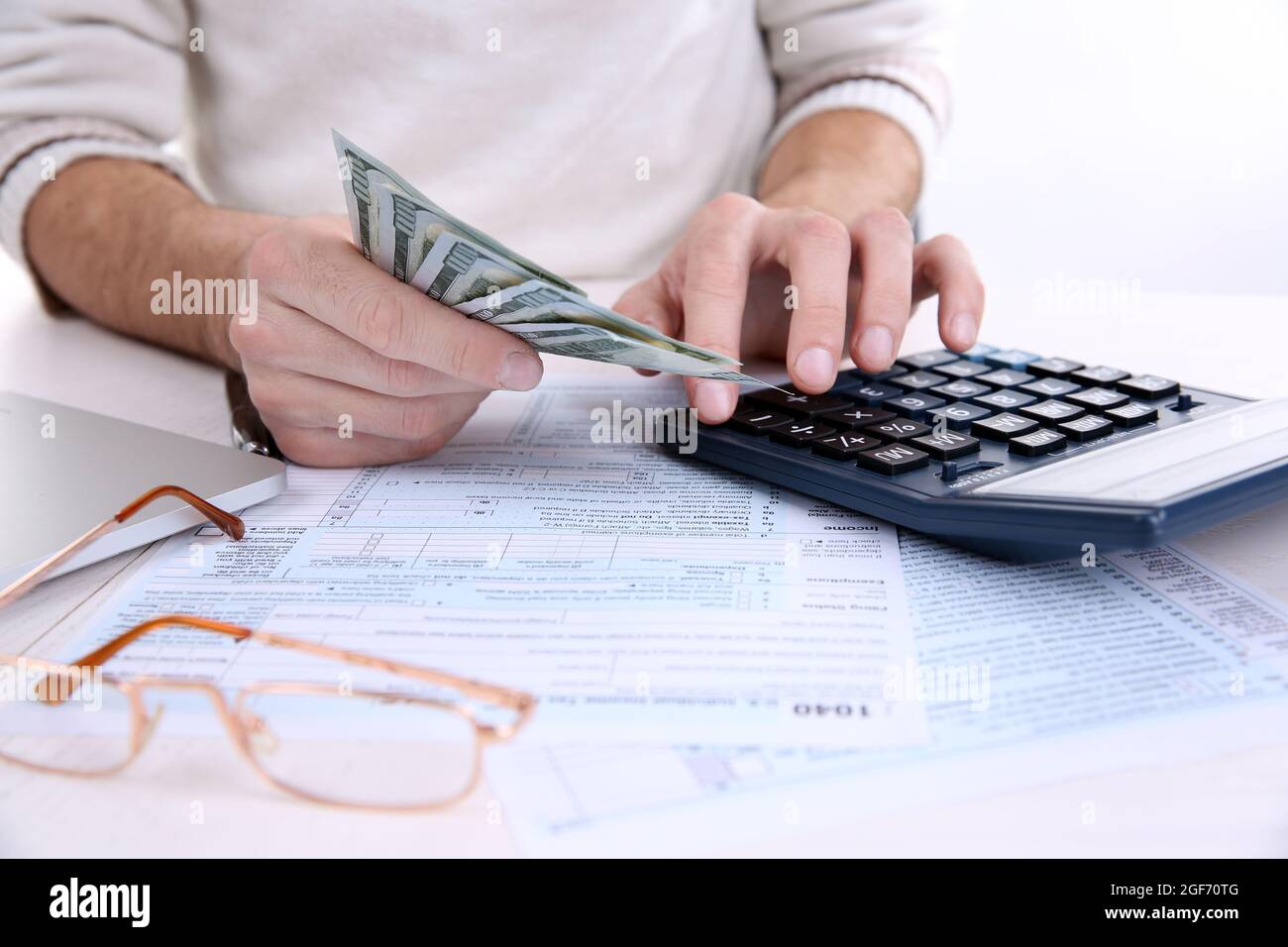 Man counting money with calculator at the table Stock Photo - Alamy