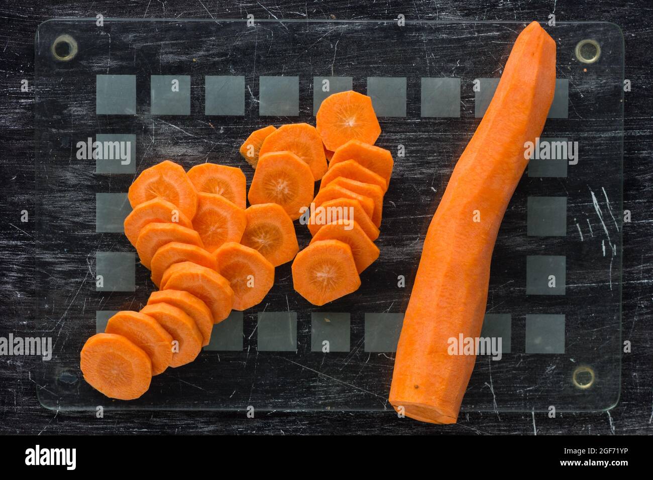 Top view of cutting on round slices raw carrot on black background ...
