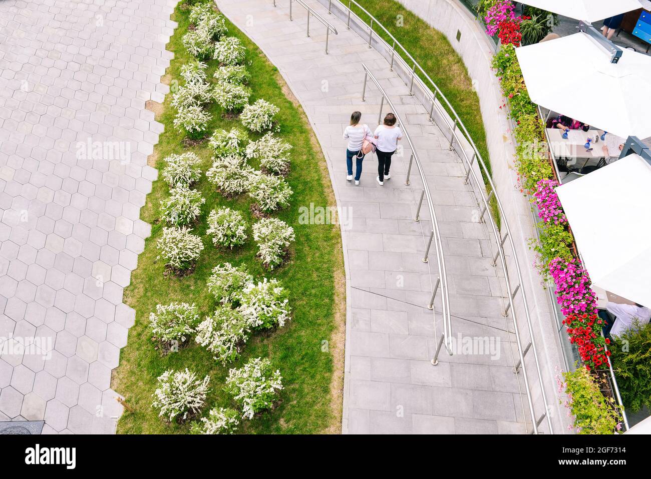 Two girls are walking in the park. People walk along the path in the ...