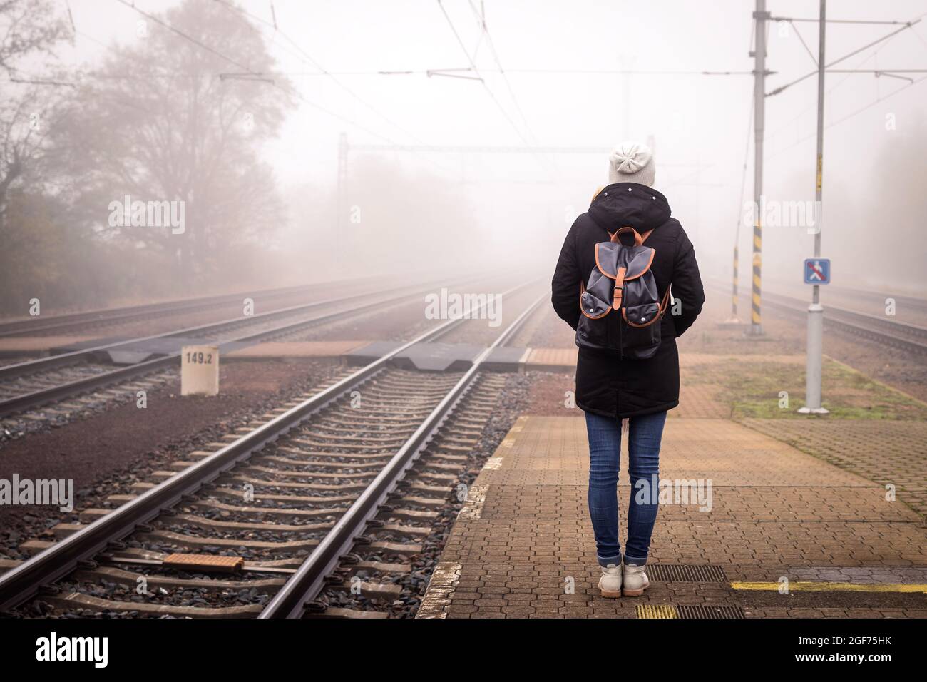Woman traveler waiting for train at railway station in foggy morning ...