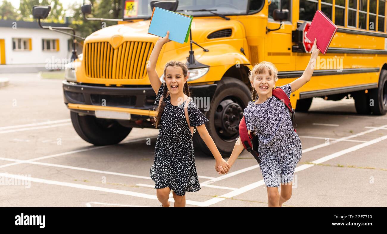 Cheerful little girls next to school bus. Backback. Back to school ...
