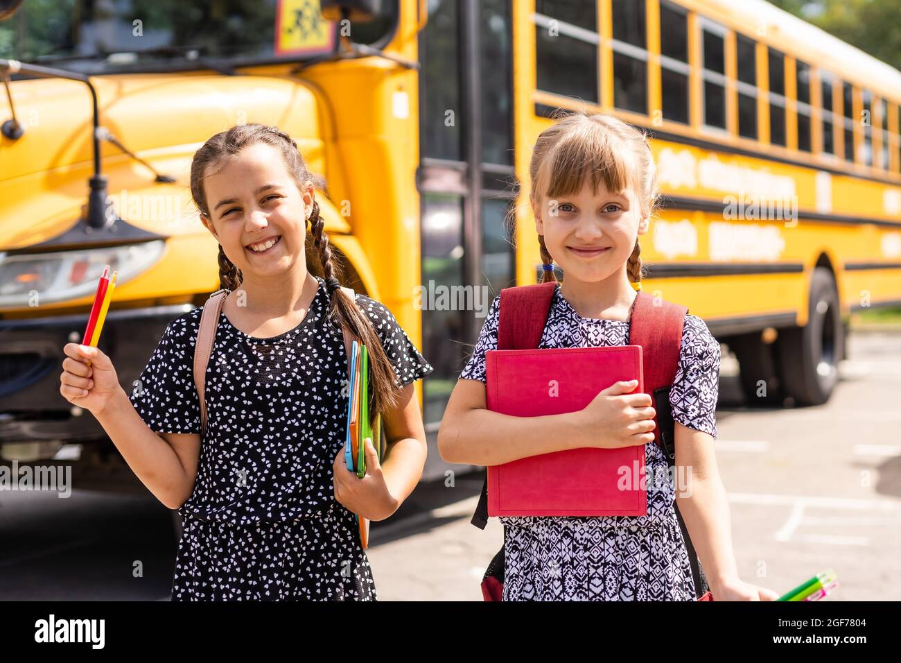Cheerful little girls next to school bus. Backback. Back to school ...