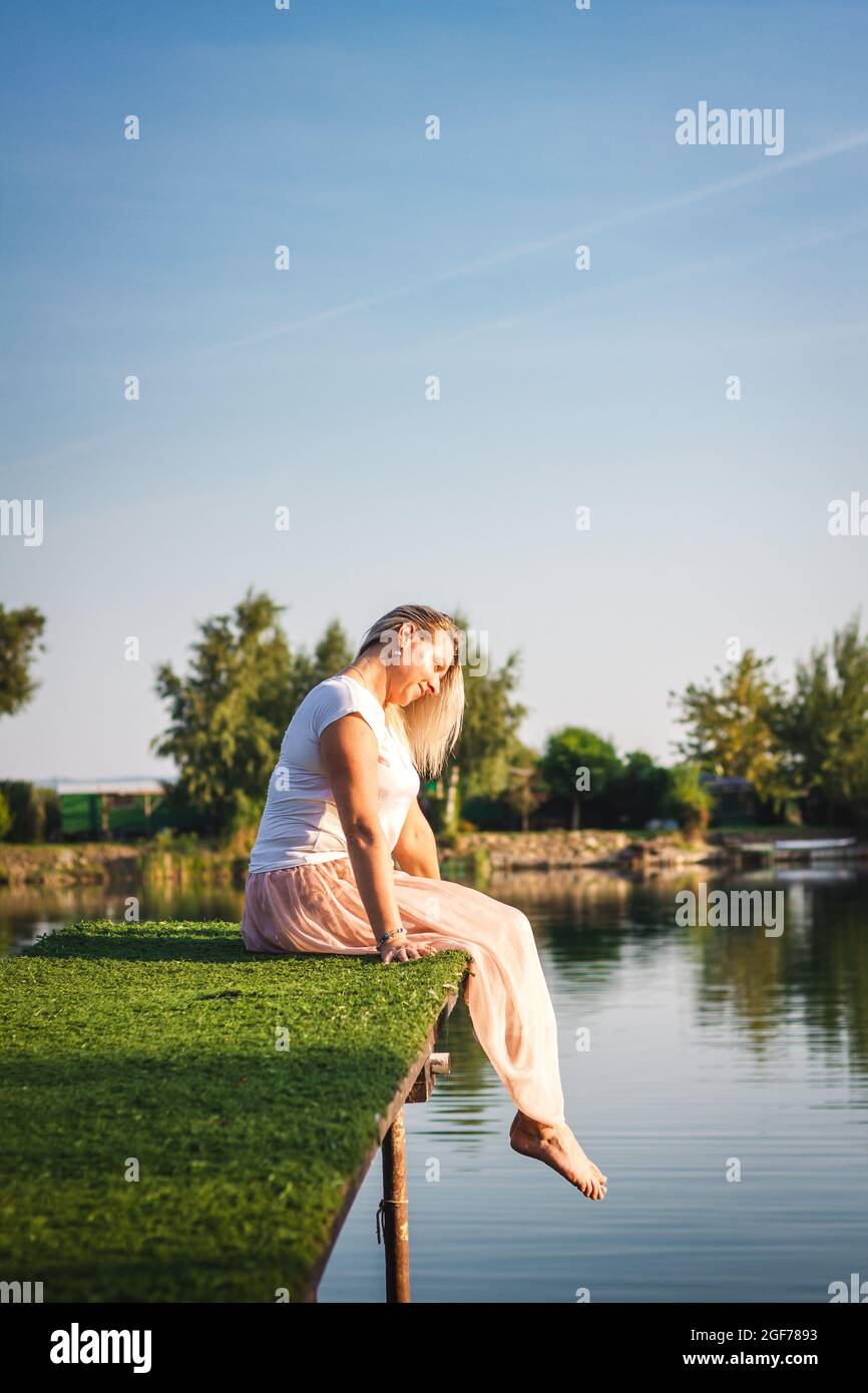 Relaxation in holiday resort at lake. Calm overweight woman sitting on ...