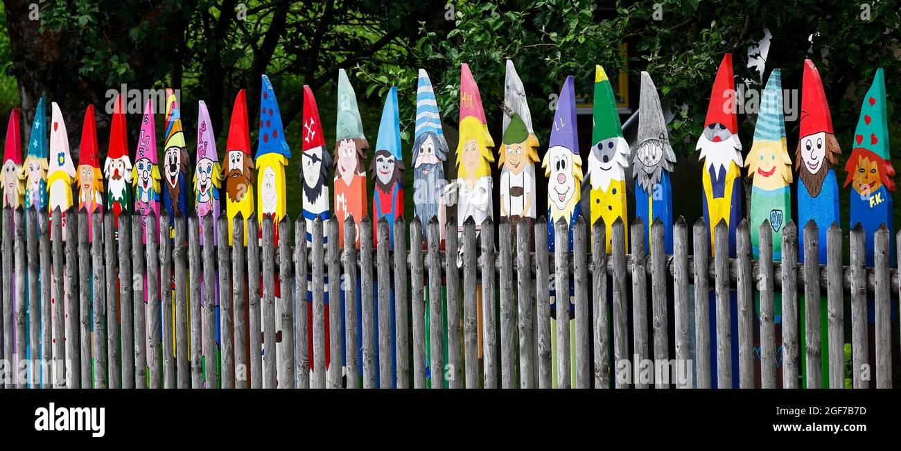 Colourfully painted funny dwarf figures behind wooden fence, Bavaria ...