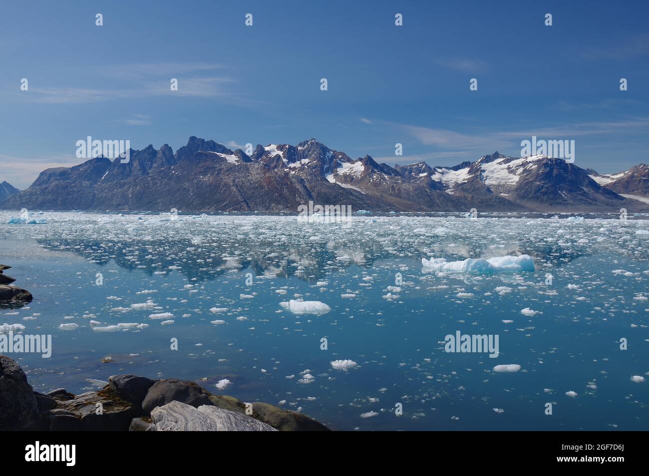 View of a fjord filled with drift ice, rugged mountains in the ...