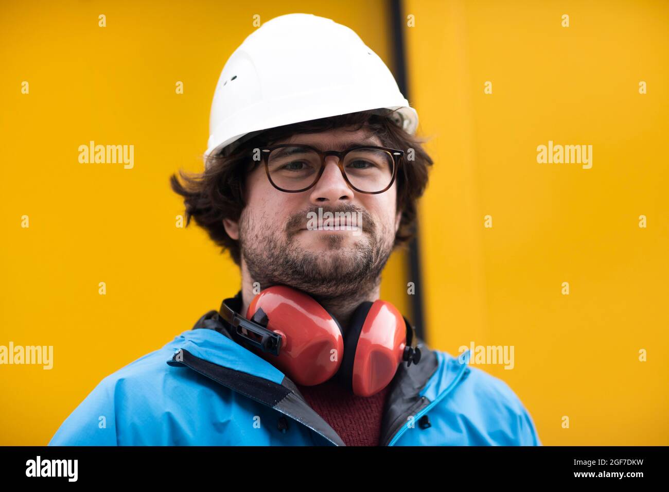 Young engineer with helmet and hearing protection at a work site ...