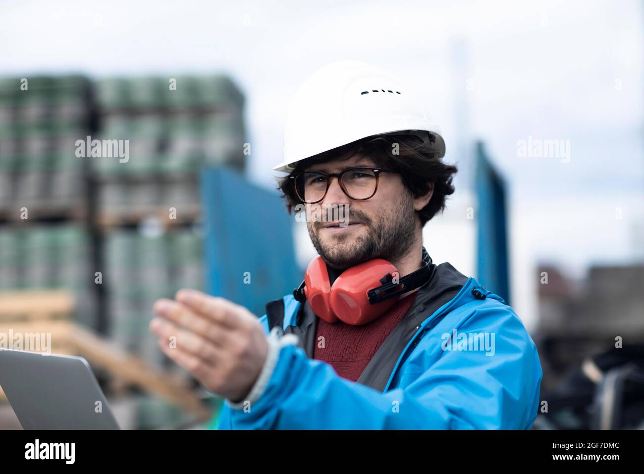 Young engineer wearing a helmet and hearing protection at a workstation ...