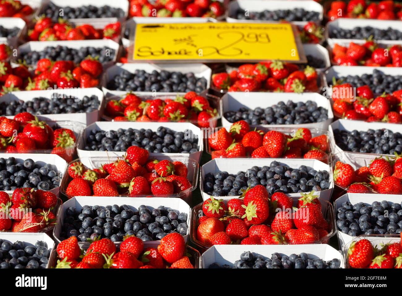 Fresh strawberries and blueberries in trays on a market stall, Bremen ...