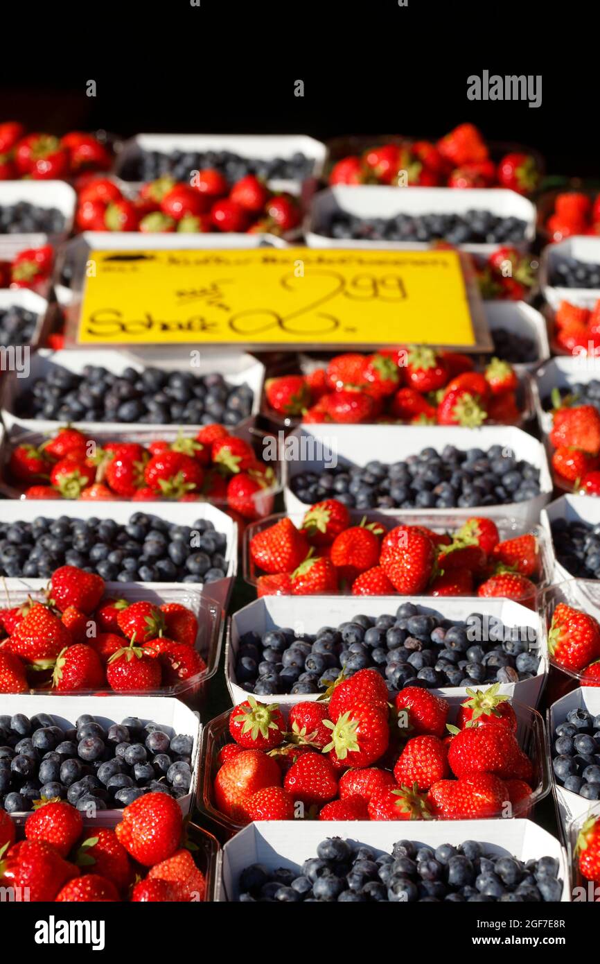 Fresh strawberries and blueberries in trays on a market stall, Bremen ...