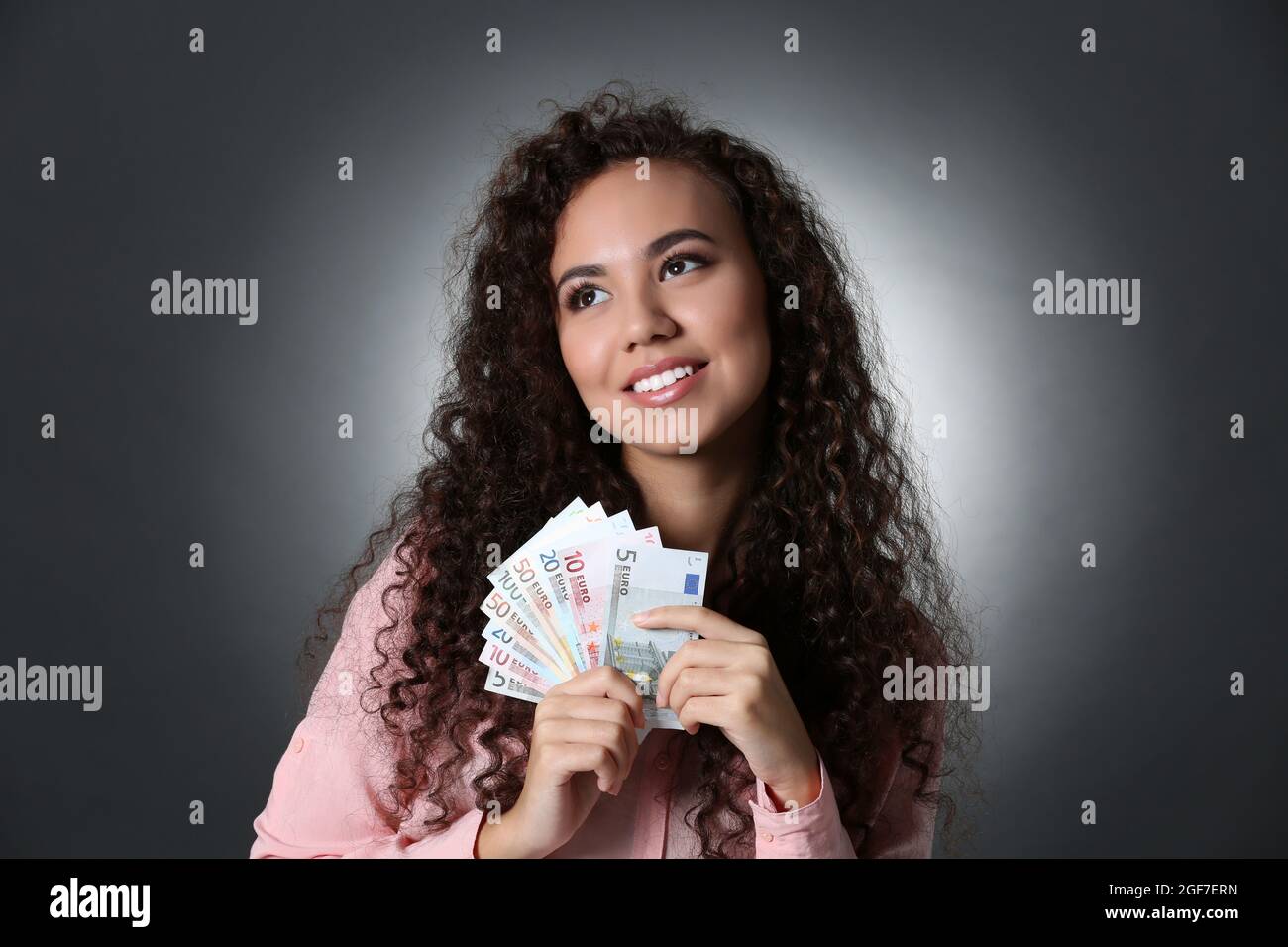 Beautiful young girl holding cash on grey background Stock Photo - Alamy