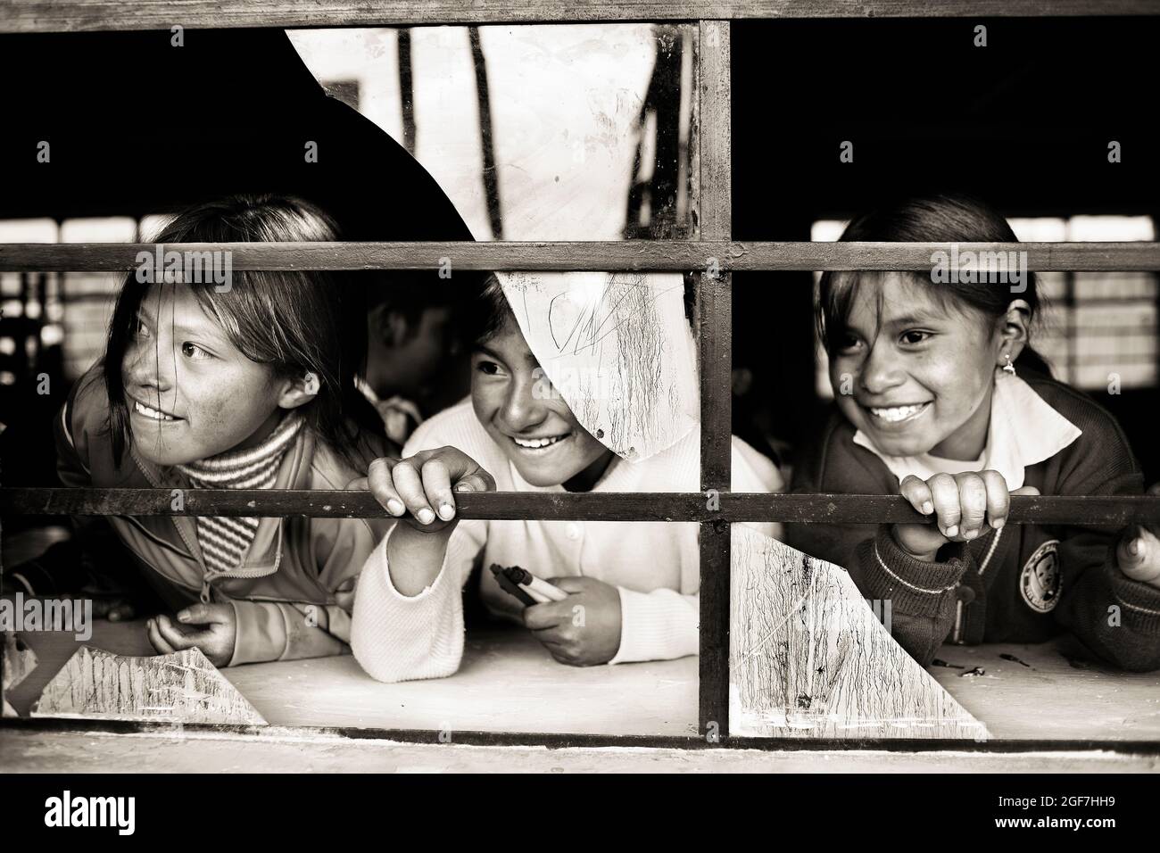 Tree schoolgirls smiling and looking through broken window Stock Photo ...