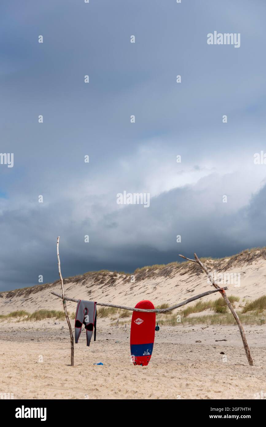 Surfboard and wetsuit, dark rain clouds above, Carcans, Gironde ...