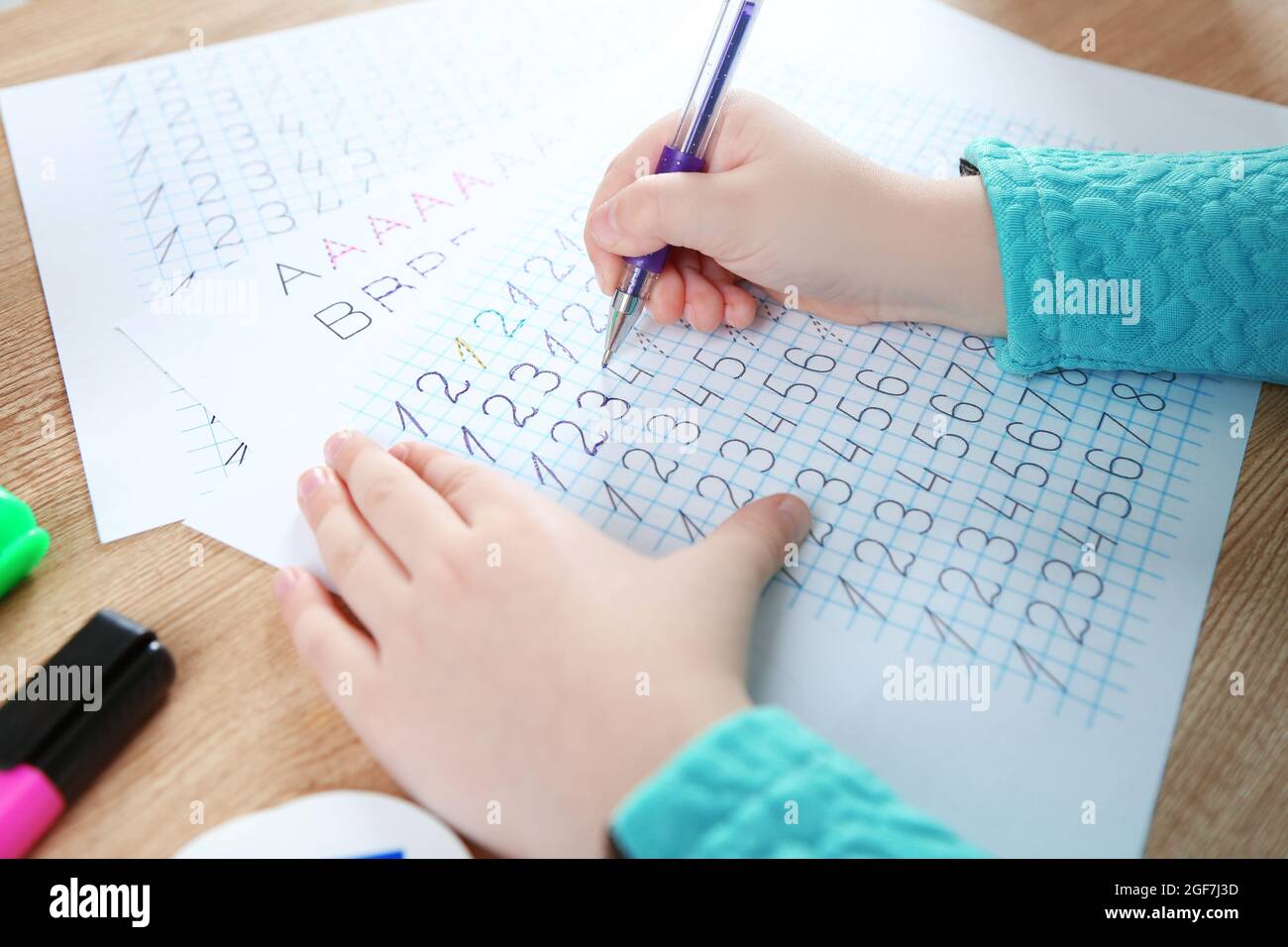 Little girl learning to write digits at the table Stock Photo - Alamy