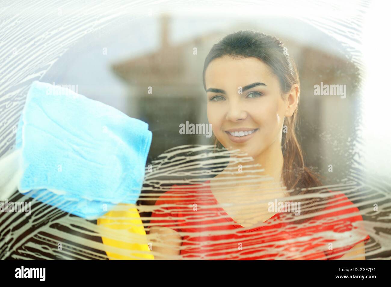 Young woman washing window glass with duster inside Stock Photo - Alamy