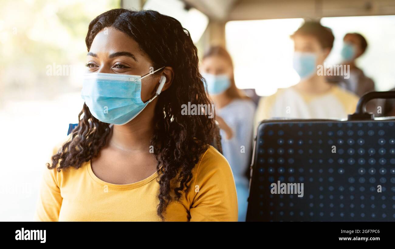Smiling black woman in mask listening to music riding bus Stock Photo - Alamy