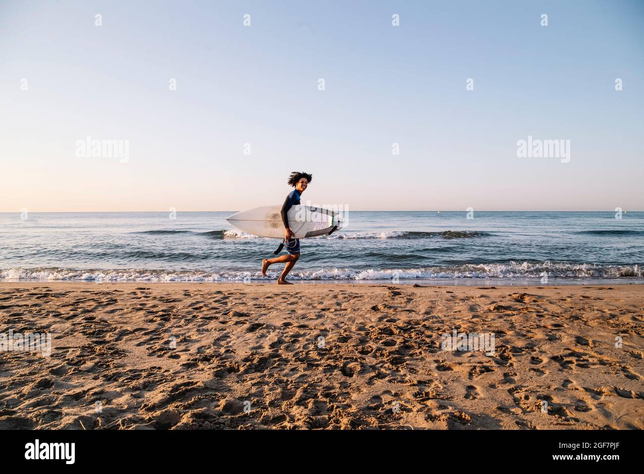 afro surfer running with surfboards along the shore Stock Photo - Alamy