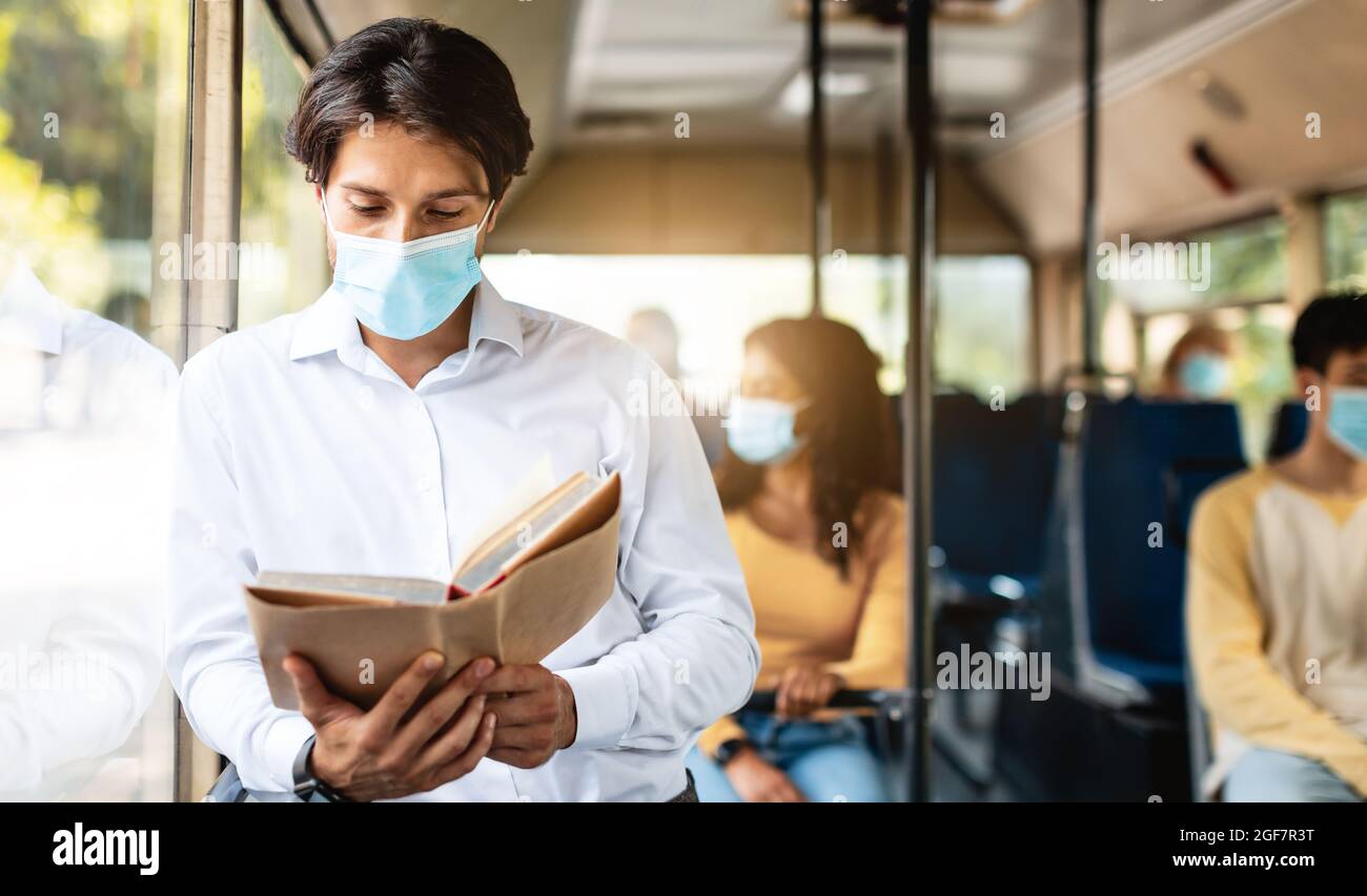 Focused business man in mask reading book riding bus Stock Photo - Alamy