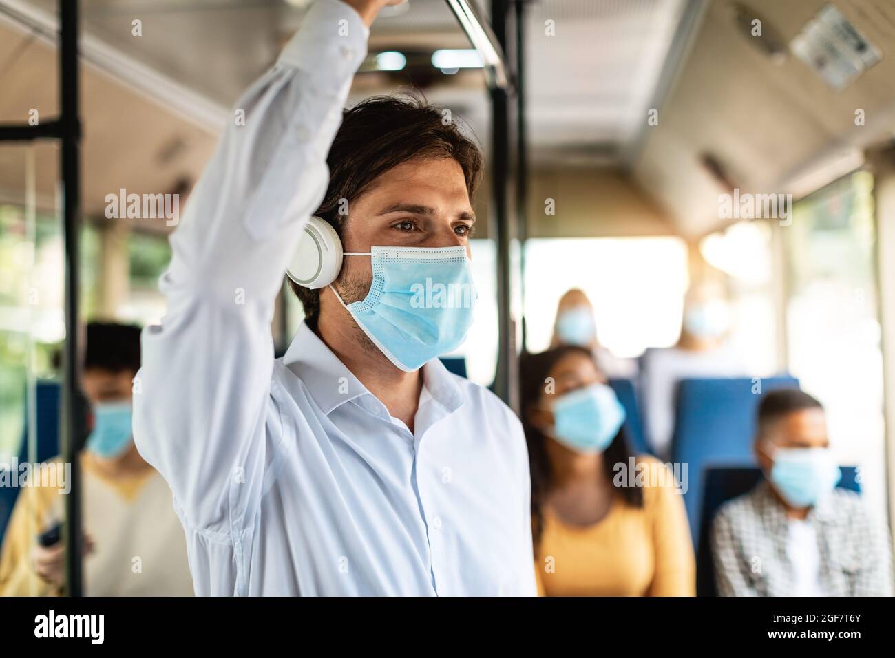 Focused business man in mask listening to music riding bus Stock Photo - Alamy
