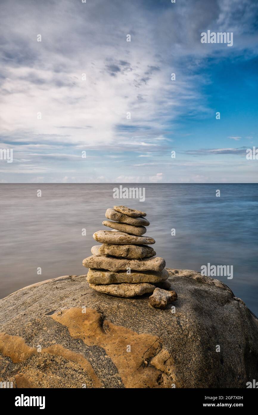 A meditative rock cairn on top of a boulder with long exposure ocean ...