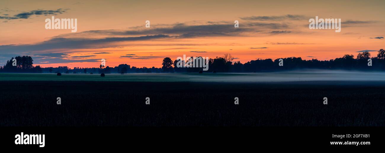 A panorama of sunset and nightfall over farm fields and forest with a ...