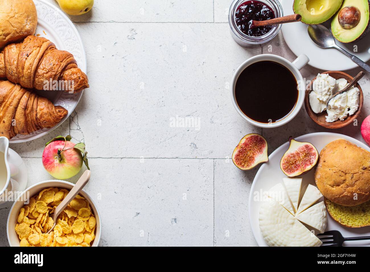 Frame of breakfast table with cornflakes, croissants, fruit, cheese and ...