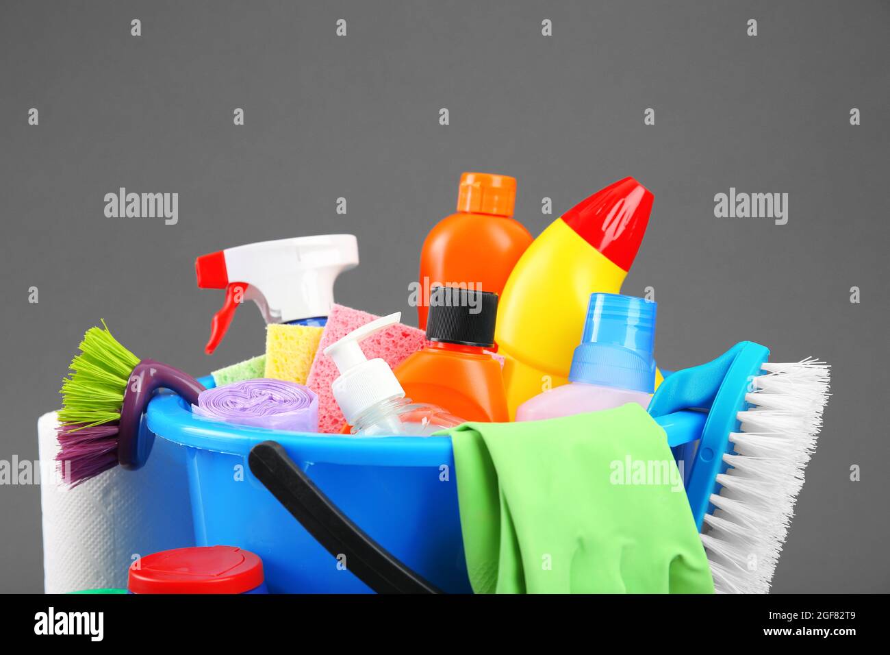 Bucket of cleaning supplies on a grey background Stock Photo - Alamy