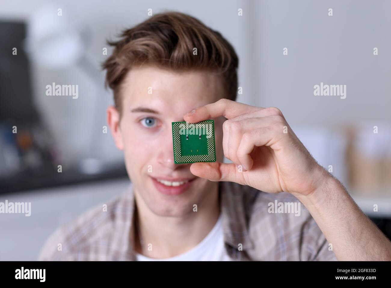 Young man holding computer processor near eye Stock Photo - Alamy