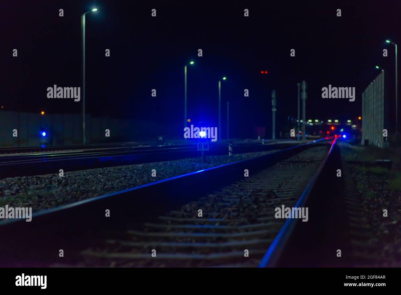 Night empty railroad tracks near train station with lights in dark ...