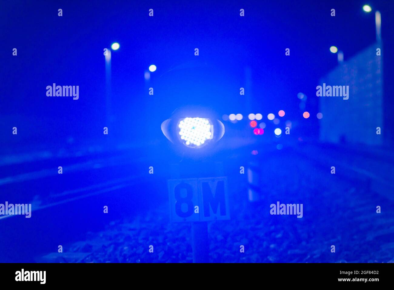 The blue traffic light at the night railway station glows blue. In the ...