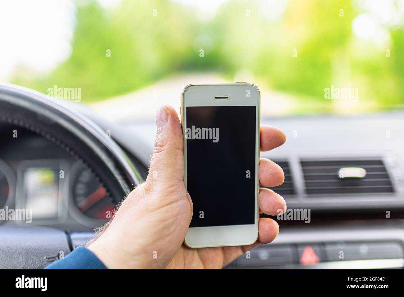 Mans hand hold and touch screen smart phone, blur on the road high way ...