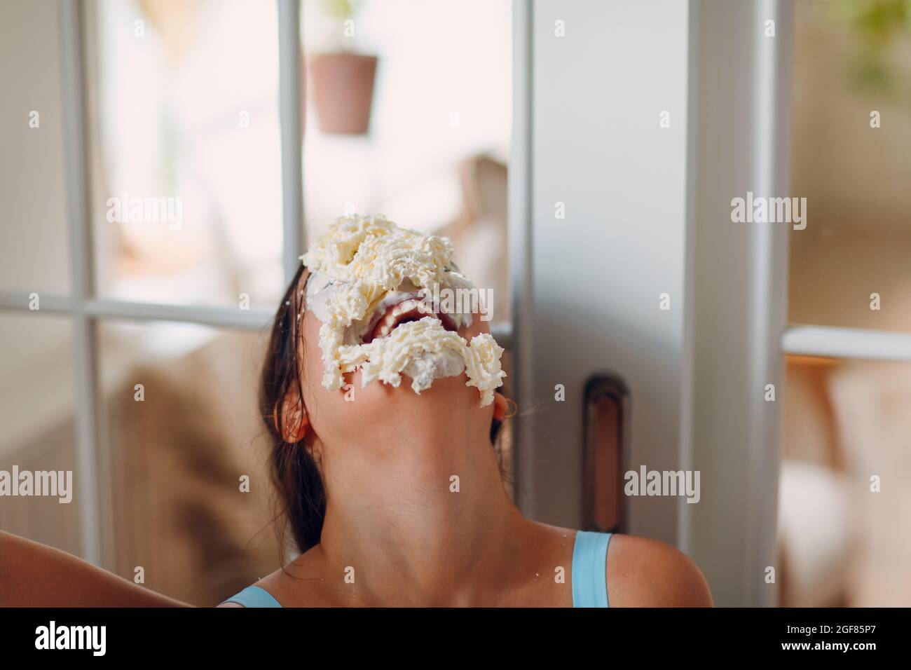 Young woman dips face in white cake with cream. Happy birthday concept ...