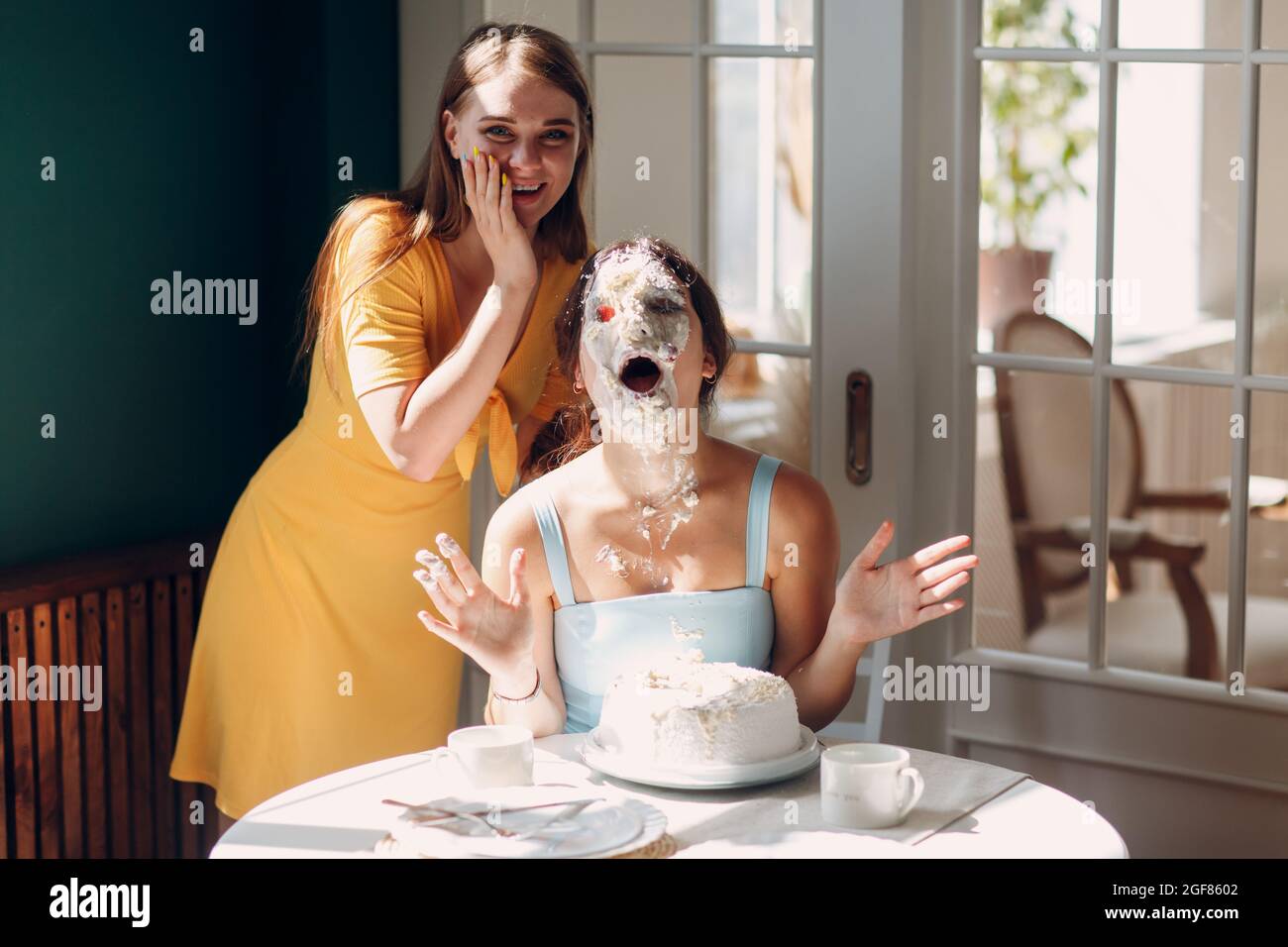 Young woman dips face in white cake with cream. Happy fun birthday ...