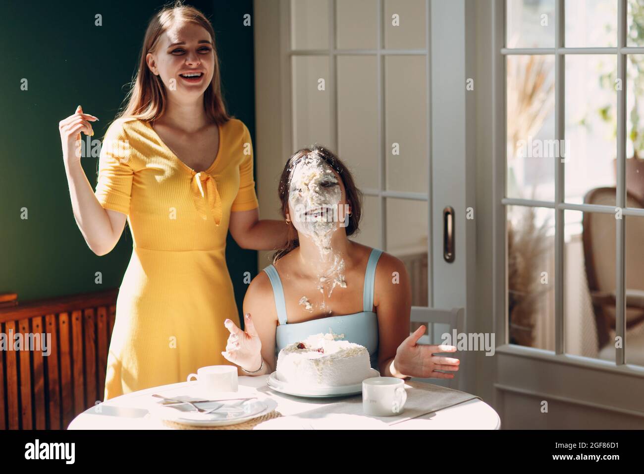 Young woman dips face in white cake with cream. Happy birthday concept ...