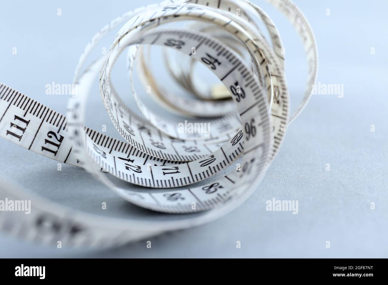 White measuring tape on a grey background Stock Photo - Alamy