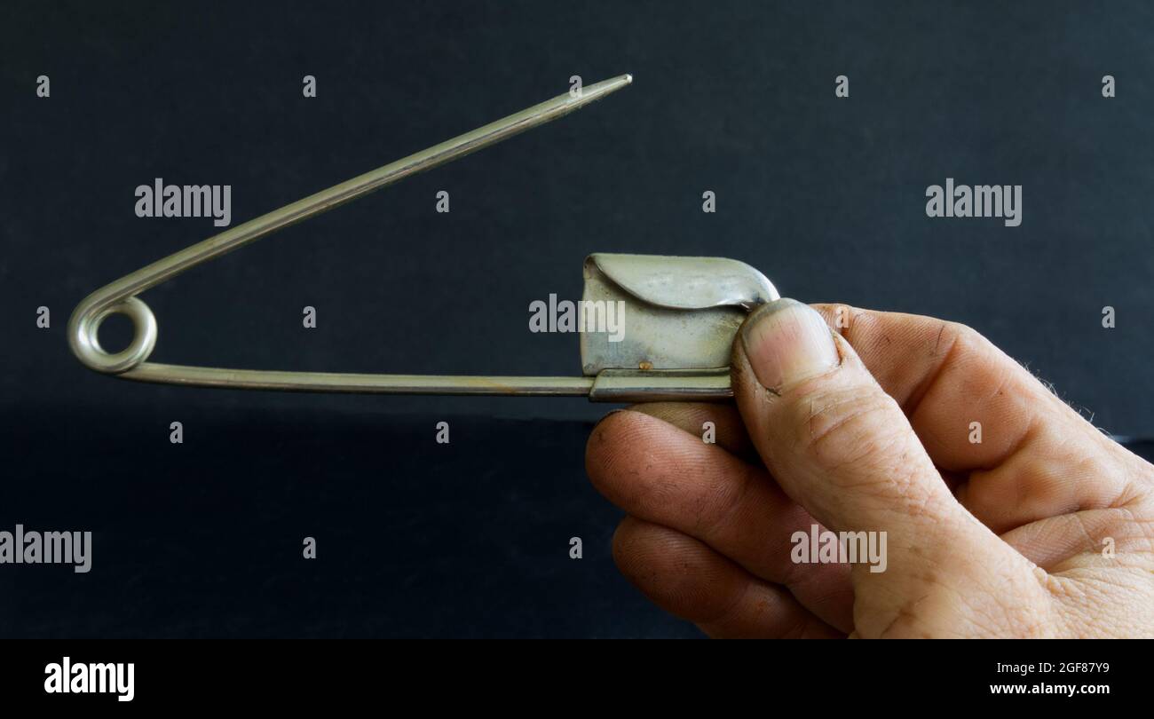 A Large Safety Pin Being Held Between a Human Thumb and Index Finger ...