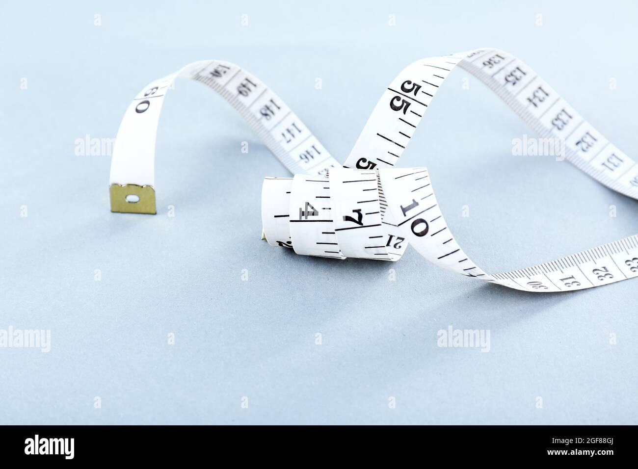 White measuring tape on a grey background Stock Photo - Alamy