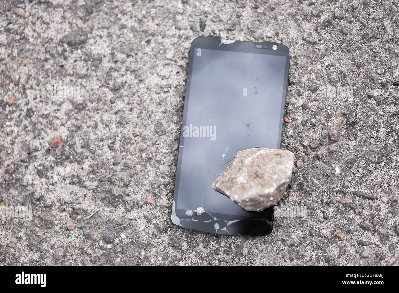Broken mobile phone with cracked screen and stone on the pavement Stock ...