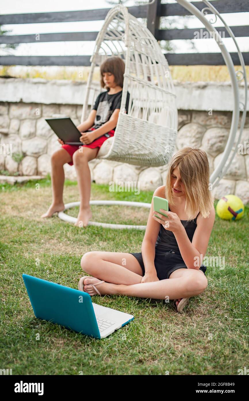 Social alienation of teenagers. Two children using laptop and ...