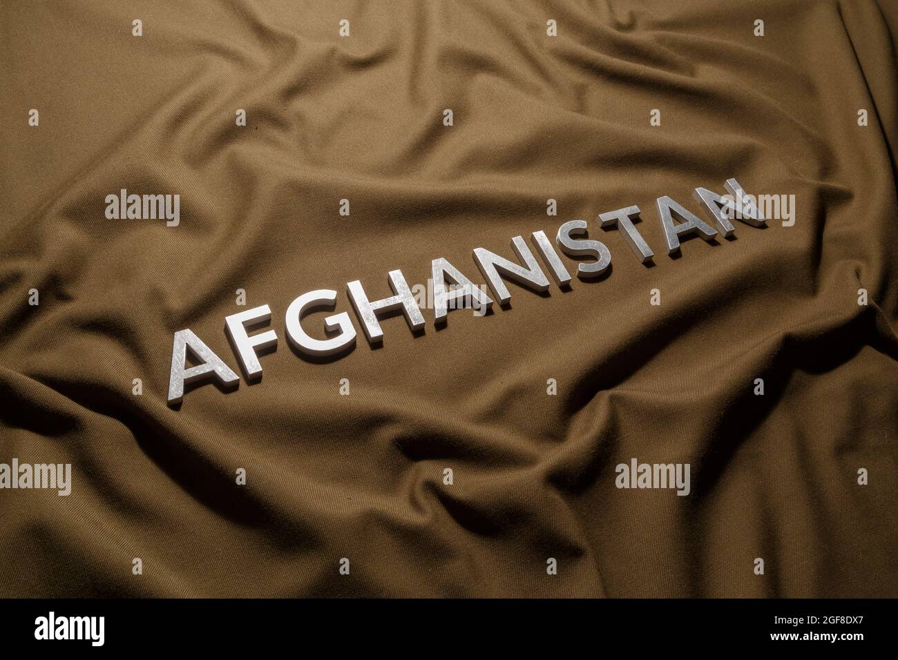 the word afghanistan laid with silver metal letters on crumpled tan ...