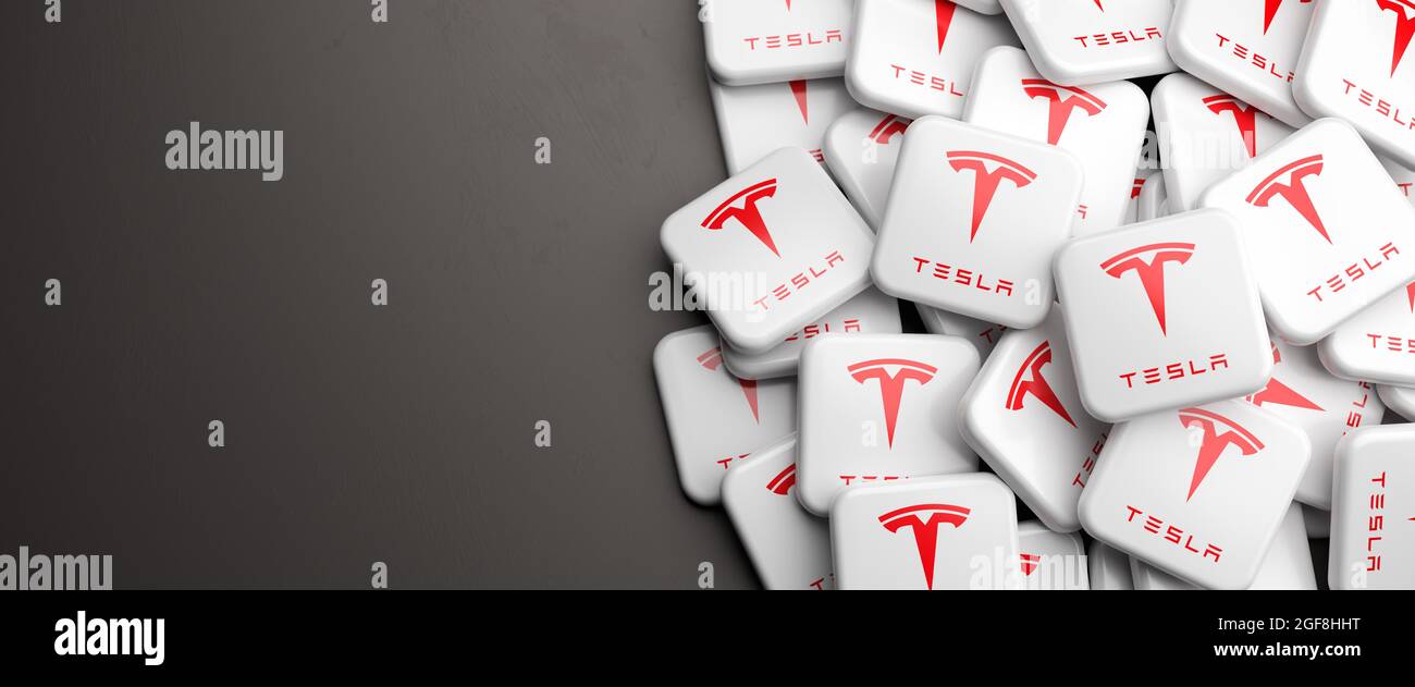 Logos of the electric car manufacturer Tesla on a heap on a table. Copy ...