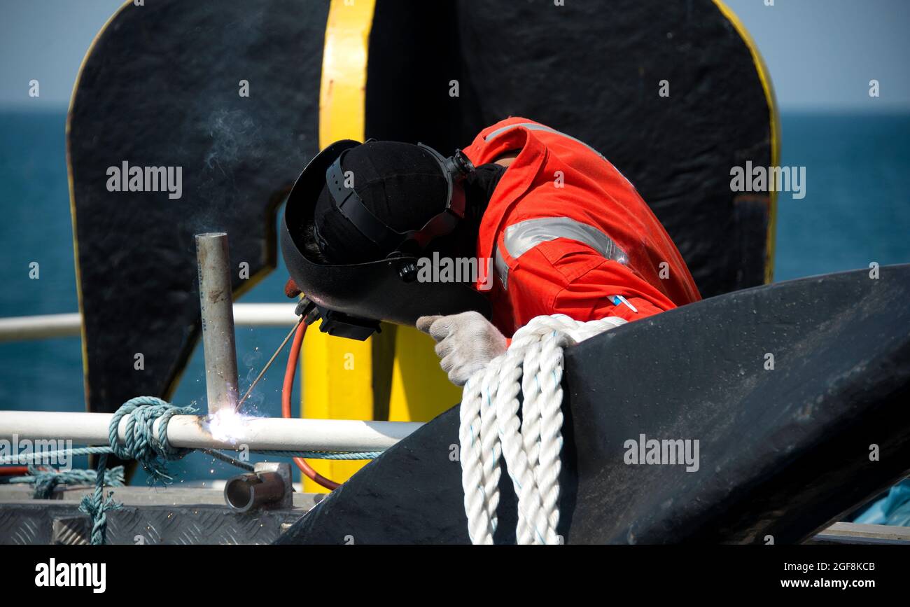 people welding pipe at sea wearing full PPE or personal protection ...