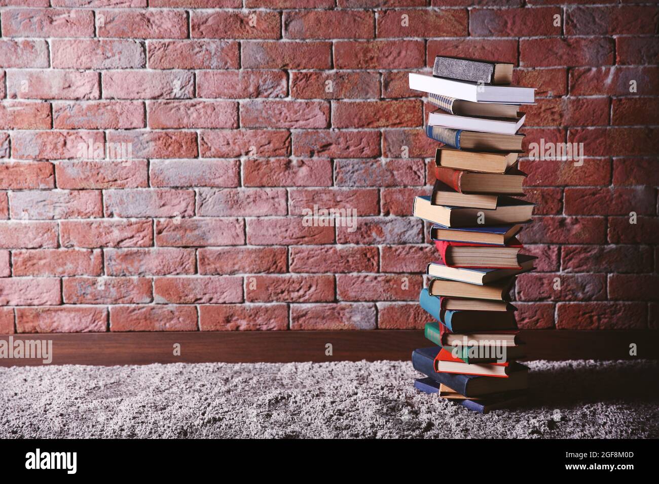 Pile of books on brick wall background Stock Photo - Alamy
