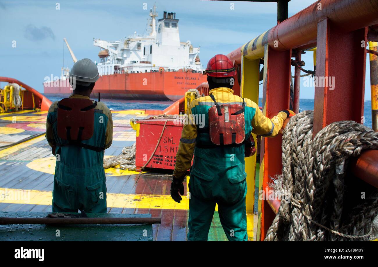 two skilled marine crew connecting cargo hose from FPSO to crude oil tanker at middle at sea ...