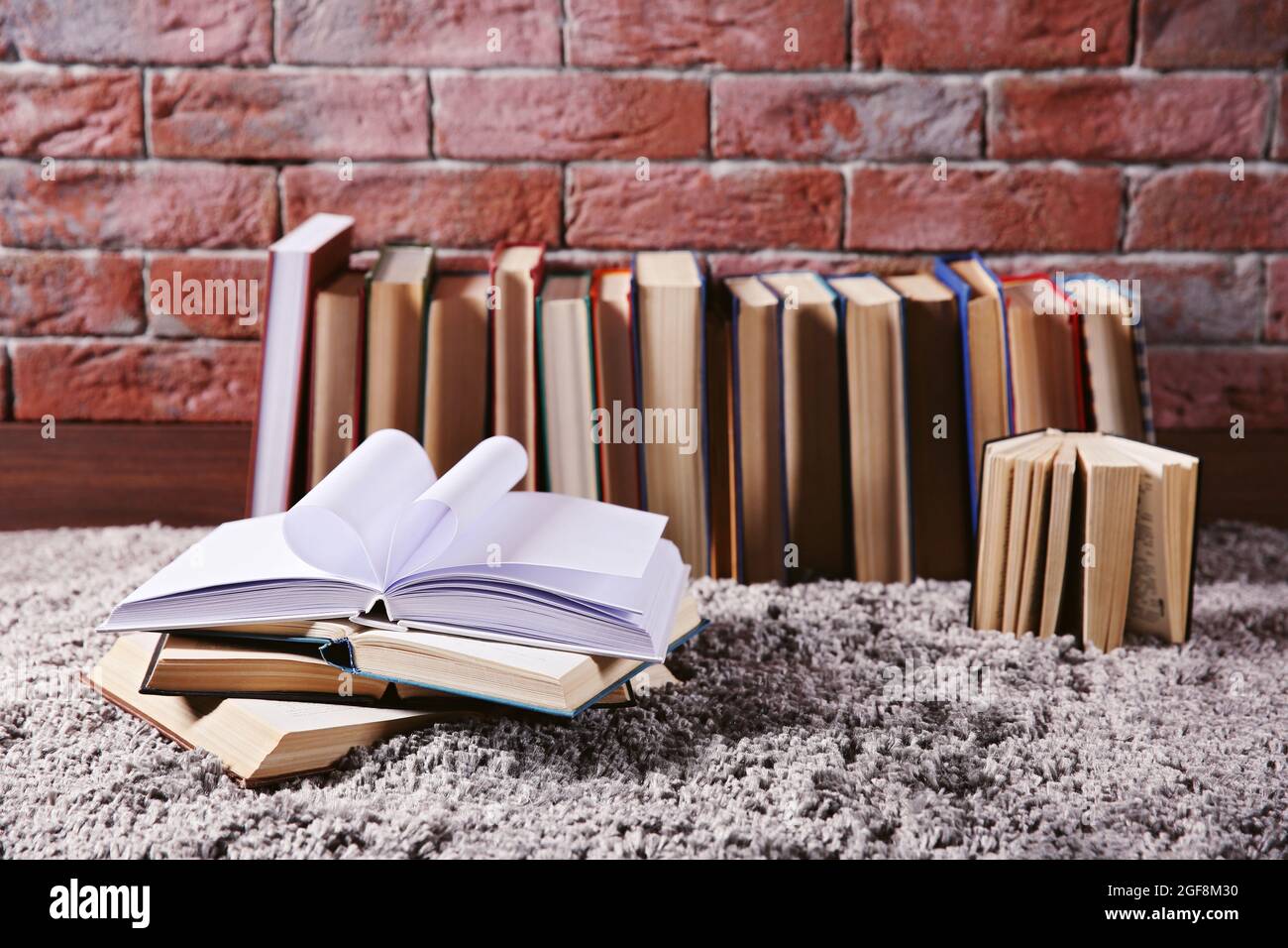 Pile of books on brick wall background Stock Photo - Alamy