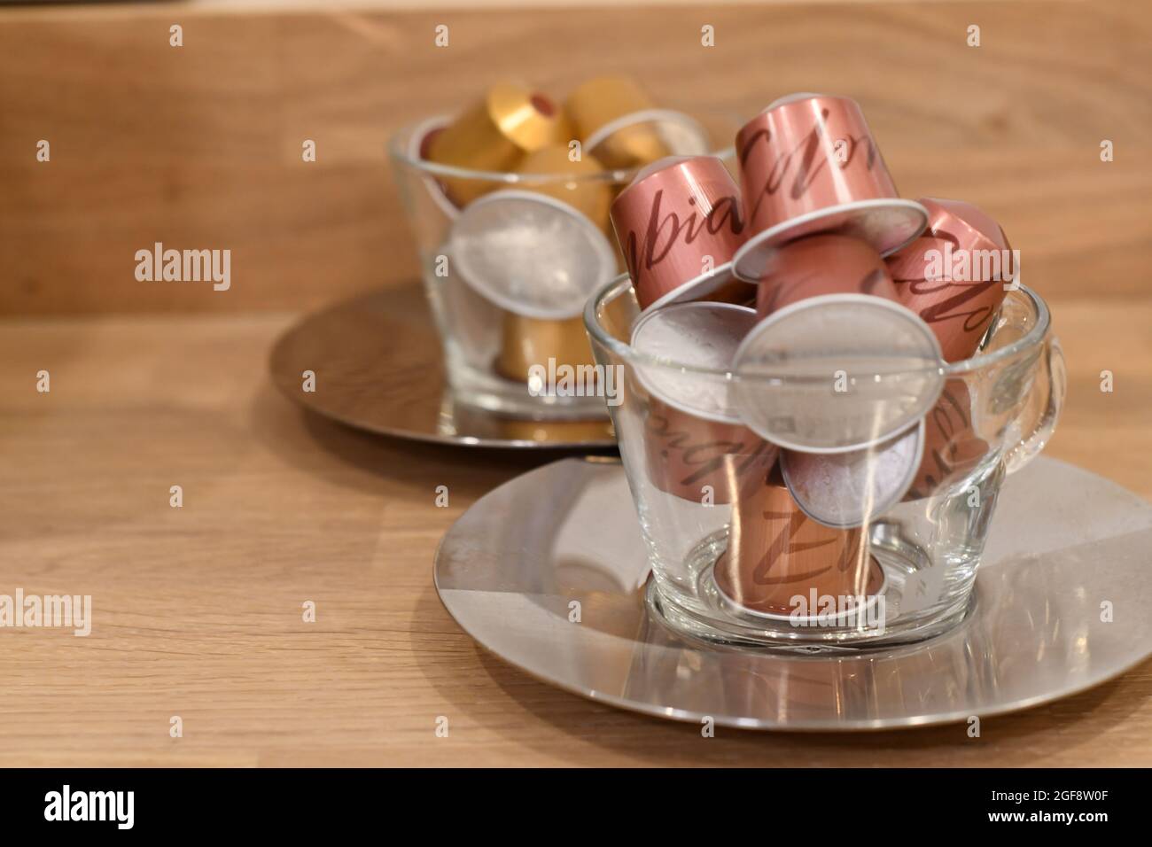 An array of coffee pods in class espresso cups and silver saucers on an ...