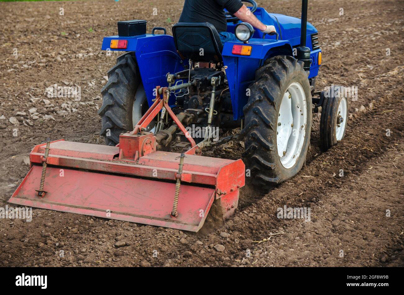 The tractor is cultivating the soil in the farm field. Freeing milling ...